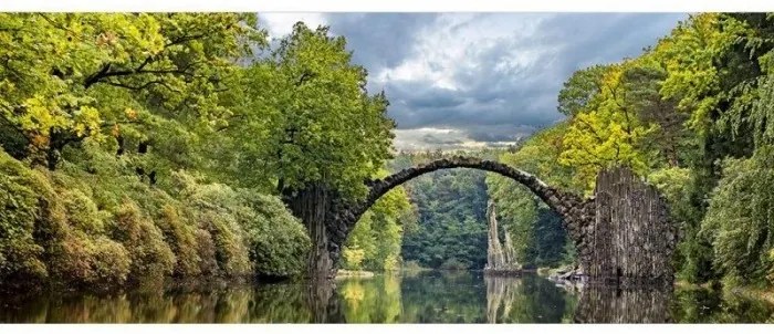 DIMEX | Panoramatická vliesová fototapeta na zeď Krajina s obloukovým mostem MP-2-0060  | 375 x 150 cm | zelená, modrá, šedá