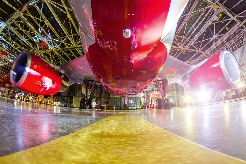 DIMEX | Samolepicí vliesová fototapeta na zeď Letadlo v hangáru MA-5-2700 | 375 x 250 cm | červená, bílá, žlutá