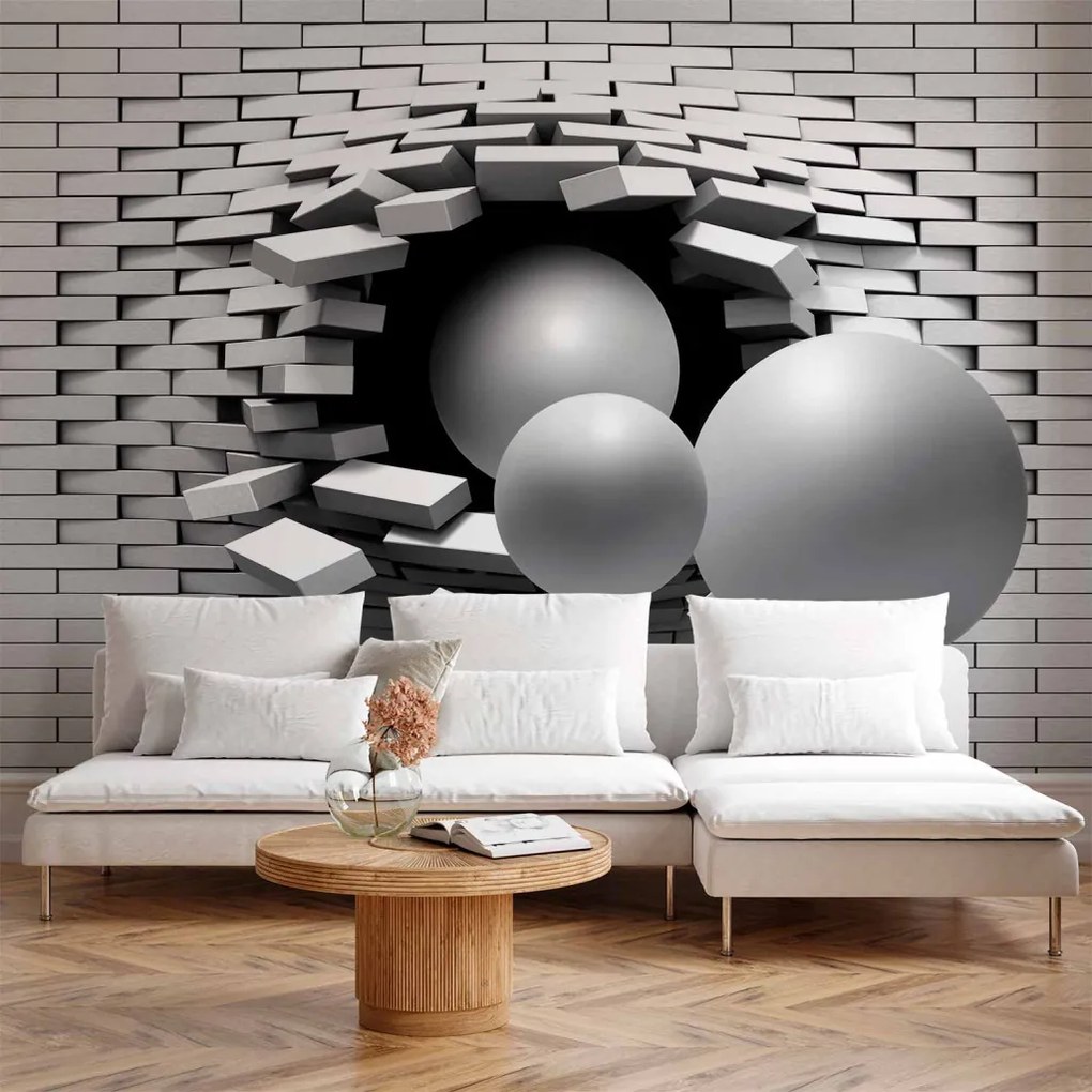 Fototapeta Díra v zdi - rozbitá cihlová bílá zeď s dírou a šedými koulemi