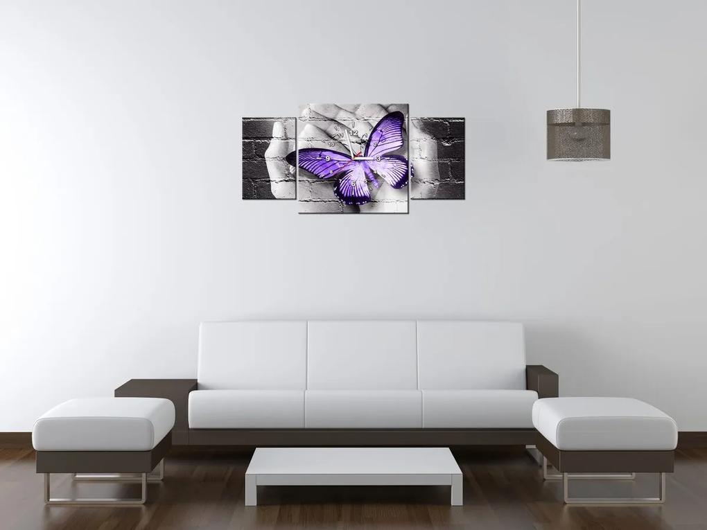 Gario Obraz s hodinami Fialový motýl na dlaních - 3 dílný Rozměry: 80 x 40 cm