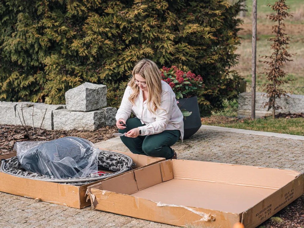 Světle šedé závěsné křeslo TROPIKAL s černým stojanem