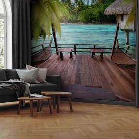 Fototapeta Tropická krajina - tyrkysová voda s palmami a dřevěnými domky